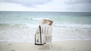Uma cadeira de praia virada para o oceano, com uma bolsa sobre ela.