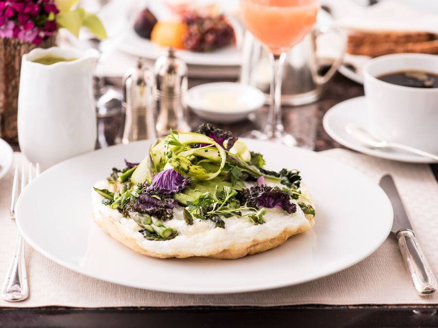 Prato de comida com diversos vegetais e uma bebida ao fundo.