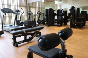 Uma academia com diversos equipamentos de exercício, incluindo esteiras, elípticos e aparelhos de musculação.