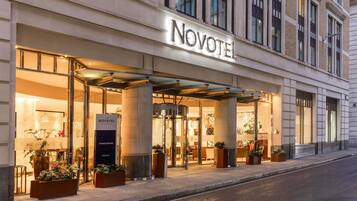 Exterior do hotel Novotel Tower Bridge, com fachada moderna, grandes janelas e uma entrada convidativa.