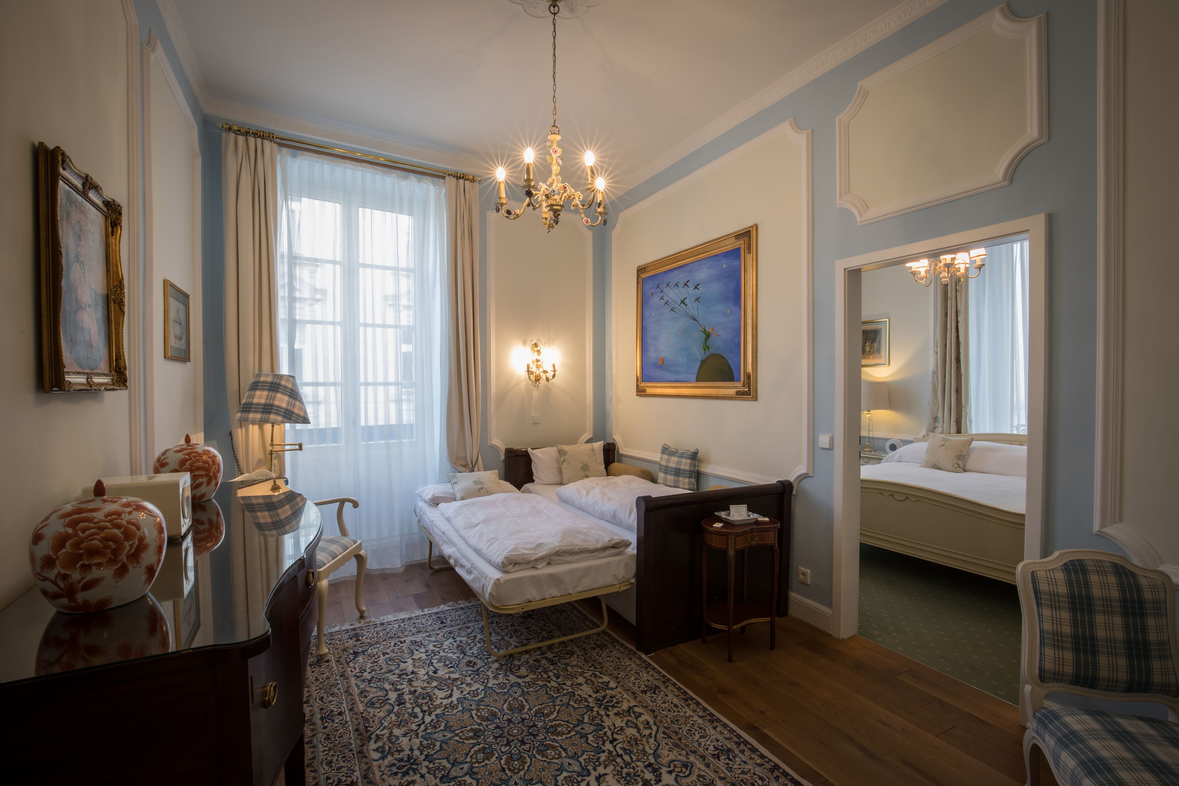 Quarto com cama, mesa de cabeceira, luminária, cadeira e um espelho grande.