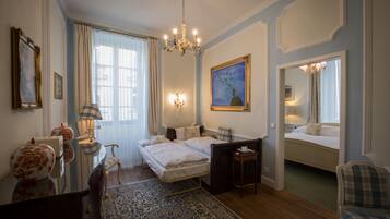 Quarto com cama, mesa de cabeceira, luminária, cadeira e um espelho grande.