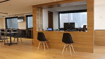 Um espaço de escritório moderno com uma mesa de recepção, duas cadeiras pretas, um laptop e um computador desktop.