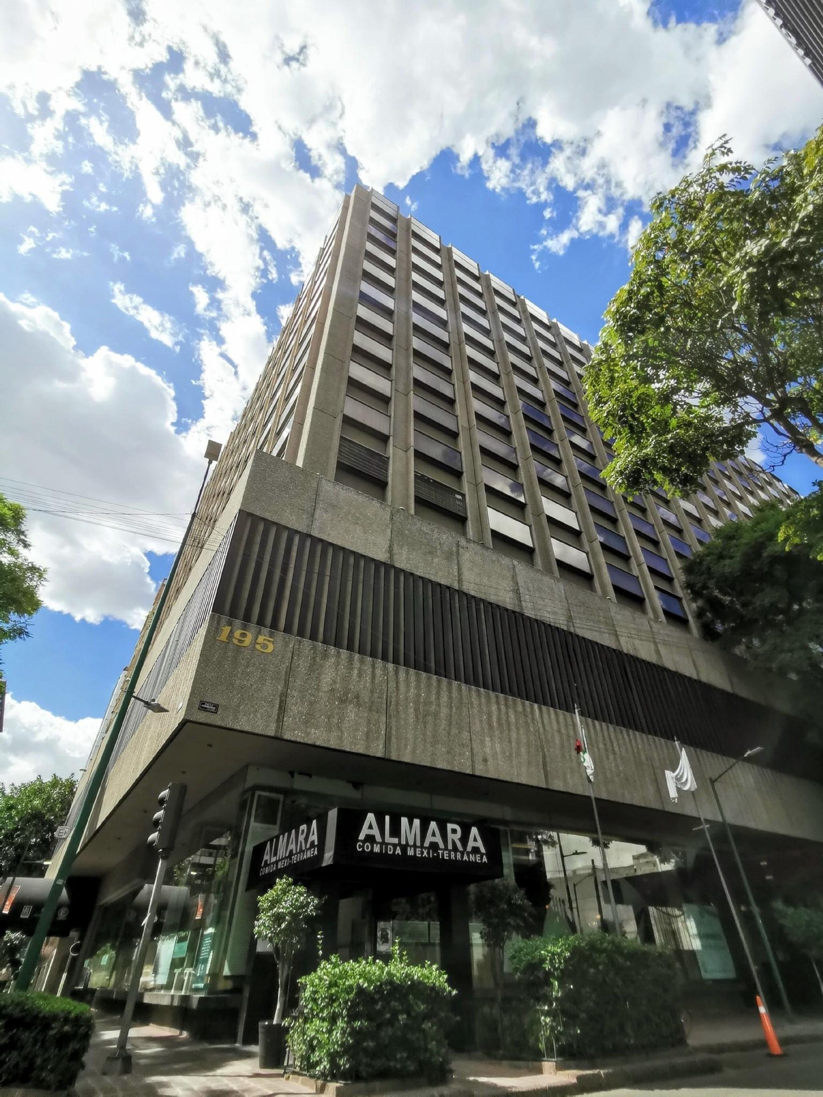 Um edifício alto com um andar térreo comercial que inclui um restaurante chamado 'Almara'.