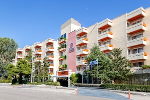 Hotel com várias varandas, uma placa vermelha em destaque e bandeiras.