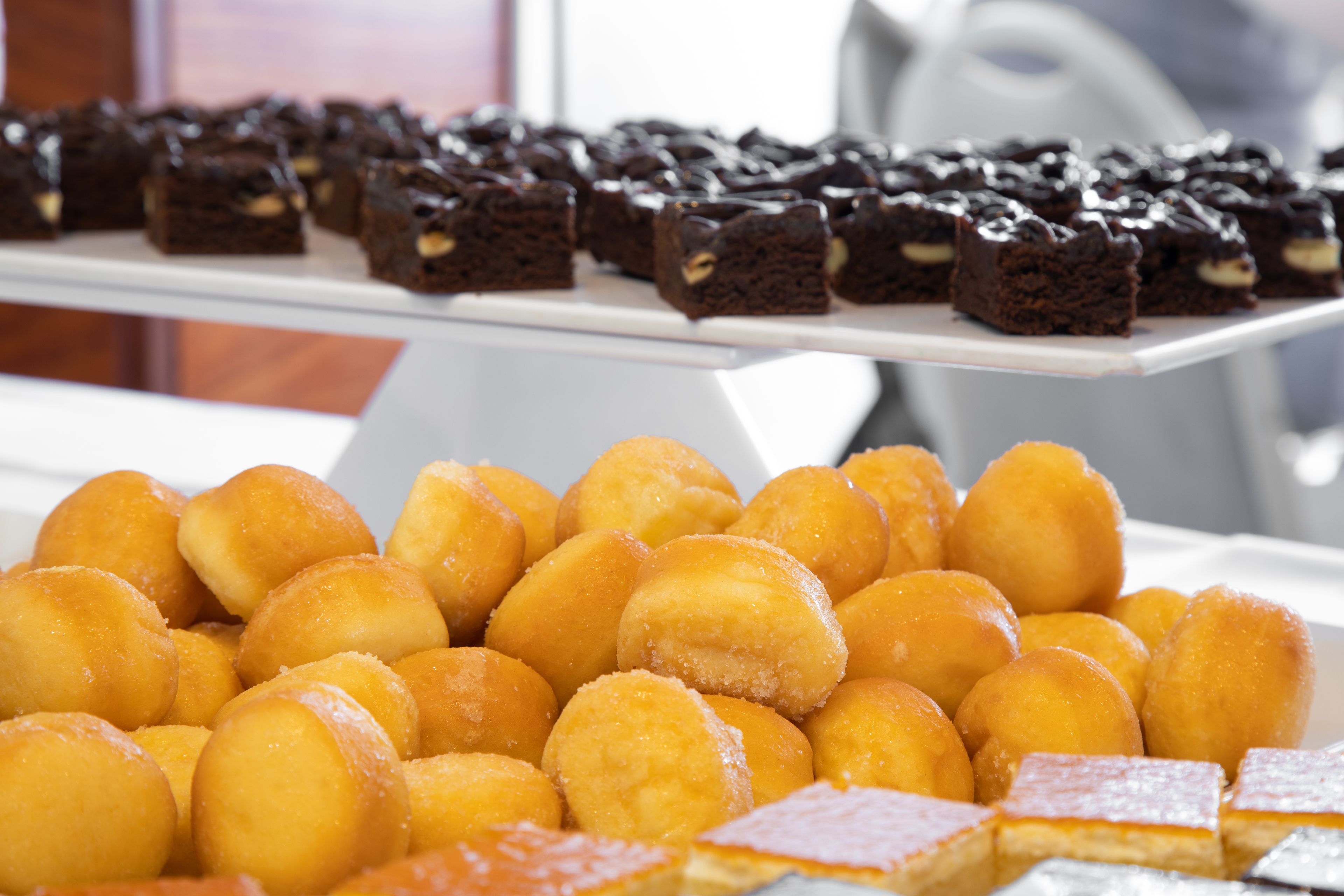 Exposição de sobremesas, incluindo brownies e donuts.