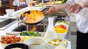Buffet com diversos alimentos e um wok em cima de um fogão.