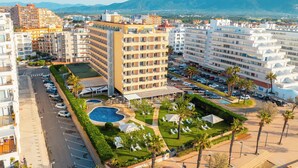 Um hotel moderno com vários sacadões, piscina e um pátio ajardinado.