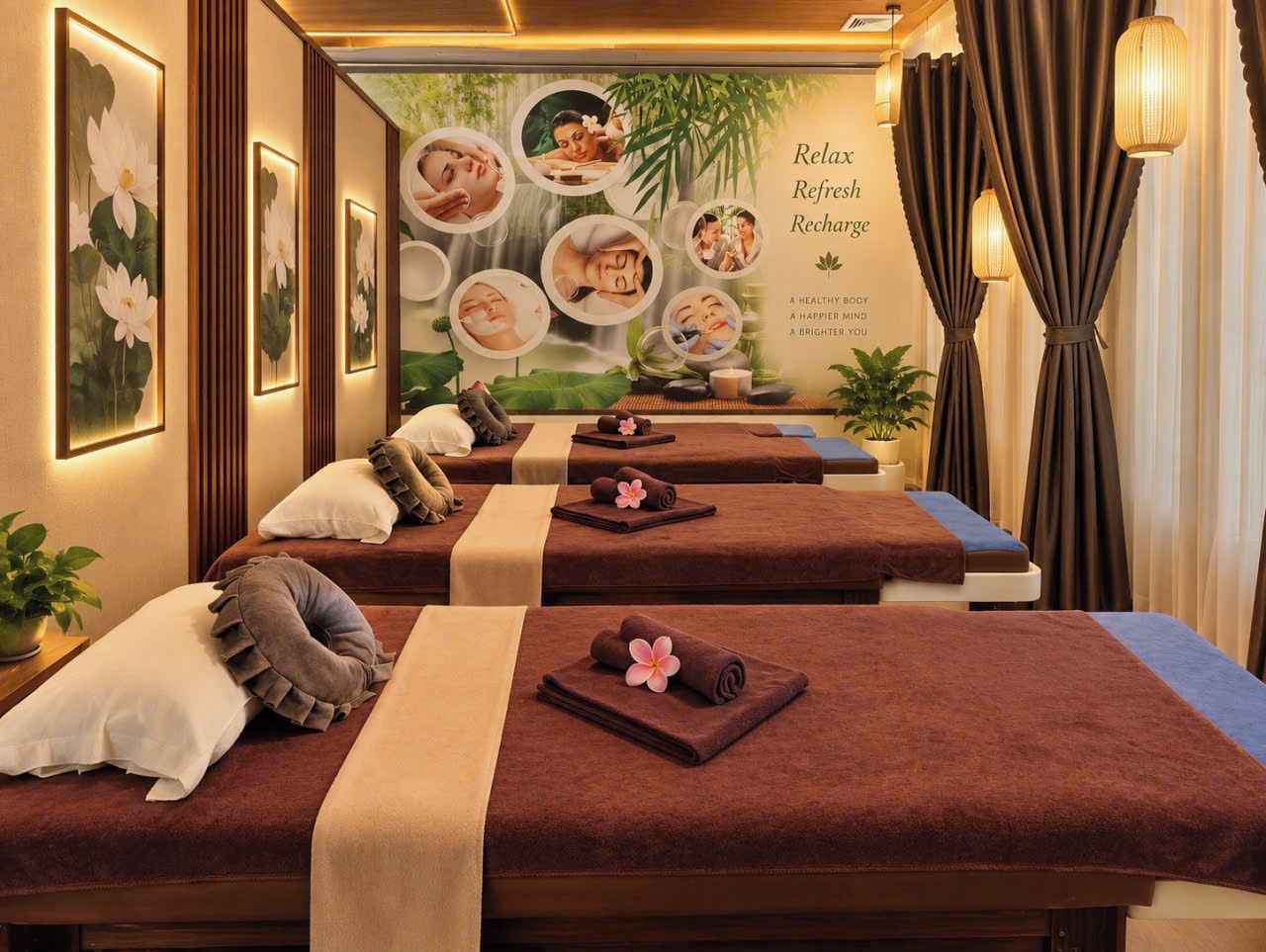 Sala de spa com mesas de massagem, toalhas e parede com imagens e texto sobre bem-estar.