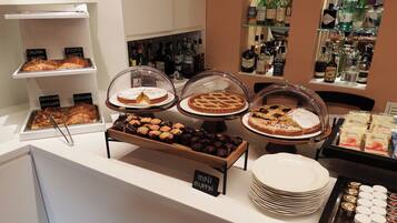 Buffet com diversos doces, seleção de mini muffins e exposição de garrafas de bebidas alcoólicas.