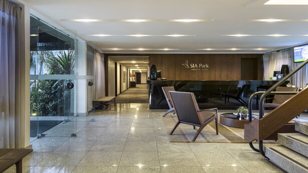 Um hall de hotel moderno com balcão de recepção, área de estar e escadas.