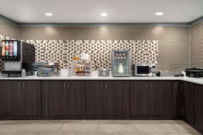 Cozinha moderna com máquina de café, micro-ondas, torradeira e frigorífico.
