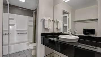 Casa de banho moderna com bancada preta, lavatório branco e cabine de duche em vidro.