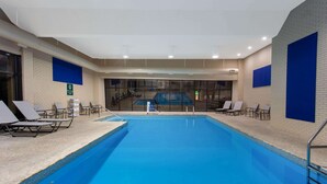 Piscina interior com espreguiçadeiras e vista clara da área da piscina.