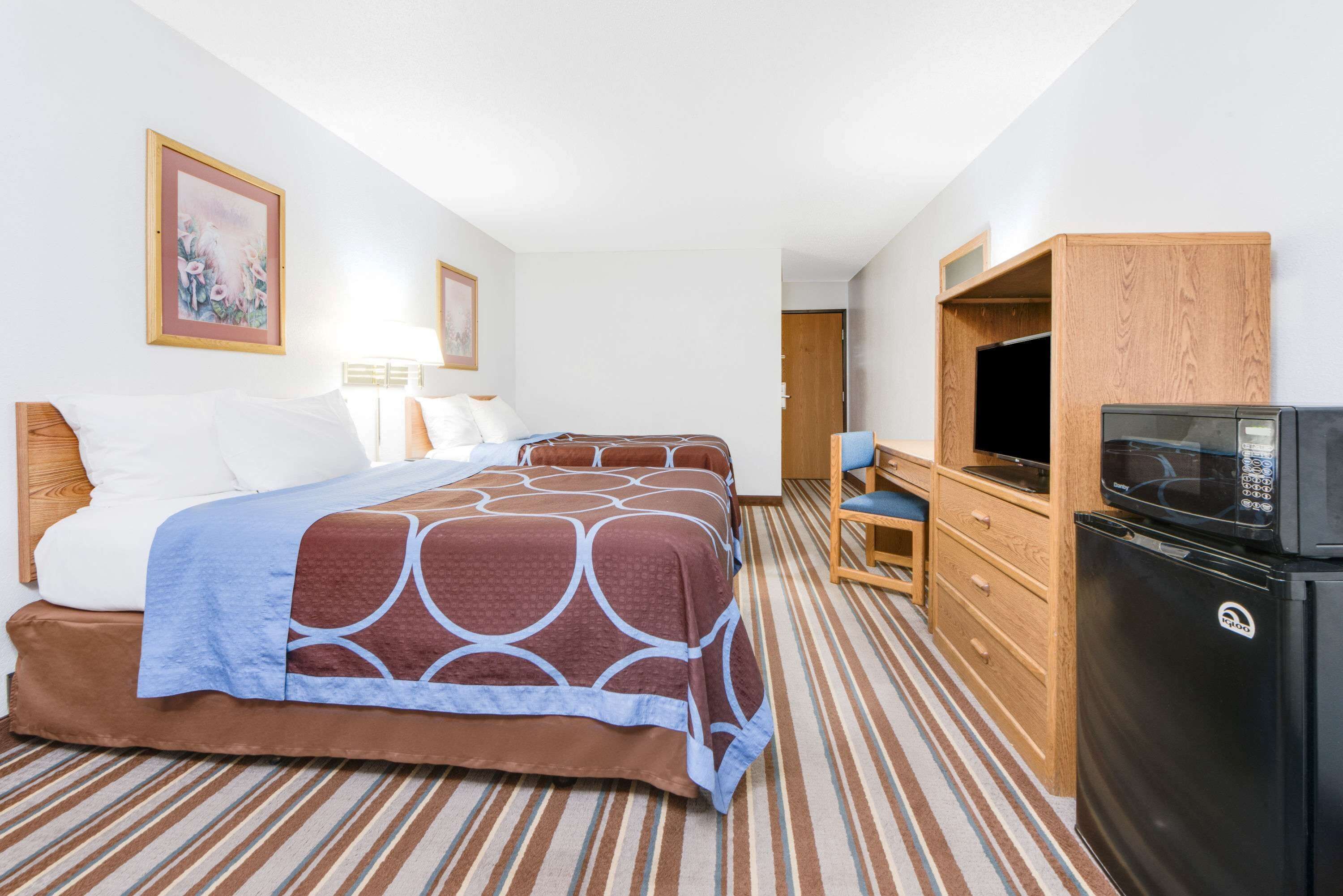 Quarto de hotel com cama, escrivaninha, televisão e frigorífico.