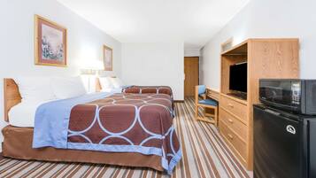 Quarto de hotel com cama, escrivaninha, televisão e frigorífico.