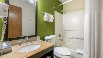 Um banheiro com parede verde, porta de madeira, pia com espelho, vaso sanitário e cortina de chuveiro.