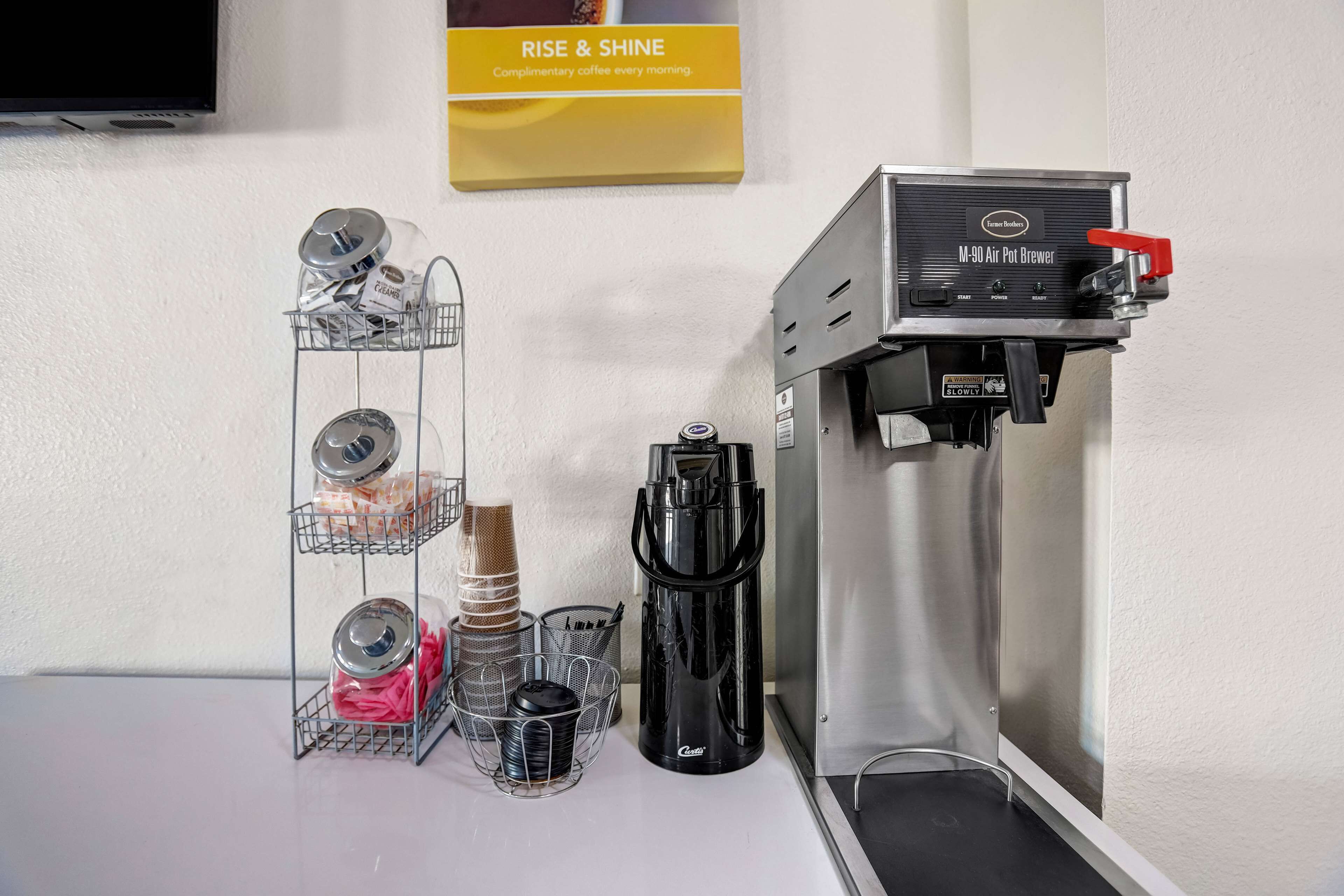 Uma estação de café com um preparador M-90 Air Pot, um moedor de café e uma cafeteira.