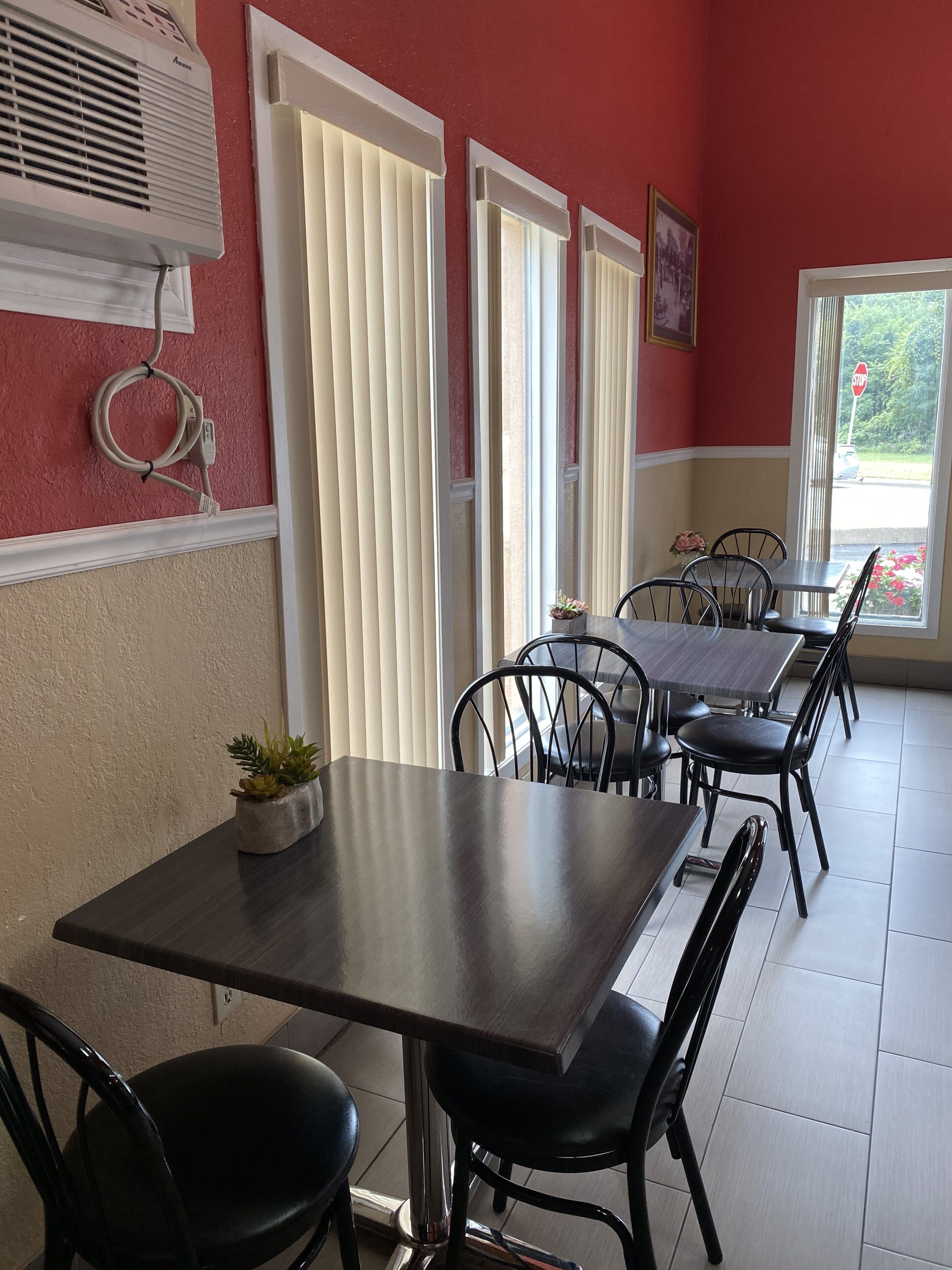 Uma área de refeições com mesa e cadeiras, um aparelho de ar condicionado e uma janela com persianas.