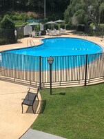 Piscina com cerca de metal preta, um banco e um poste de luz.