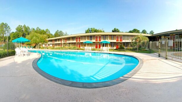 Um hotel com piscina, área de estar externa e espaço cercado.