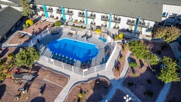 Vista aérea de um hotel com piscina, área de estar externa e jardim paisagístico.