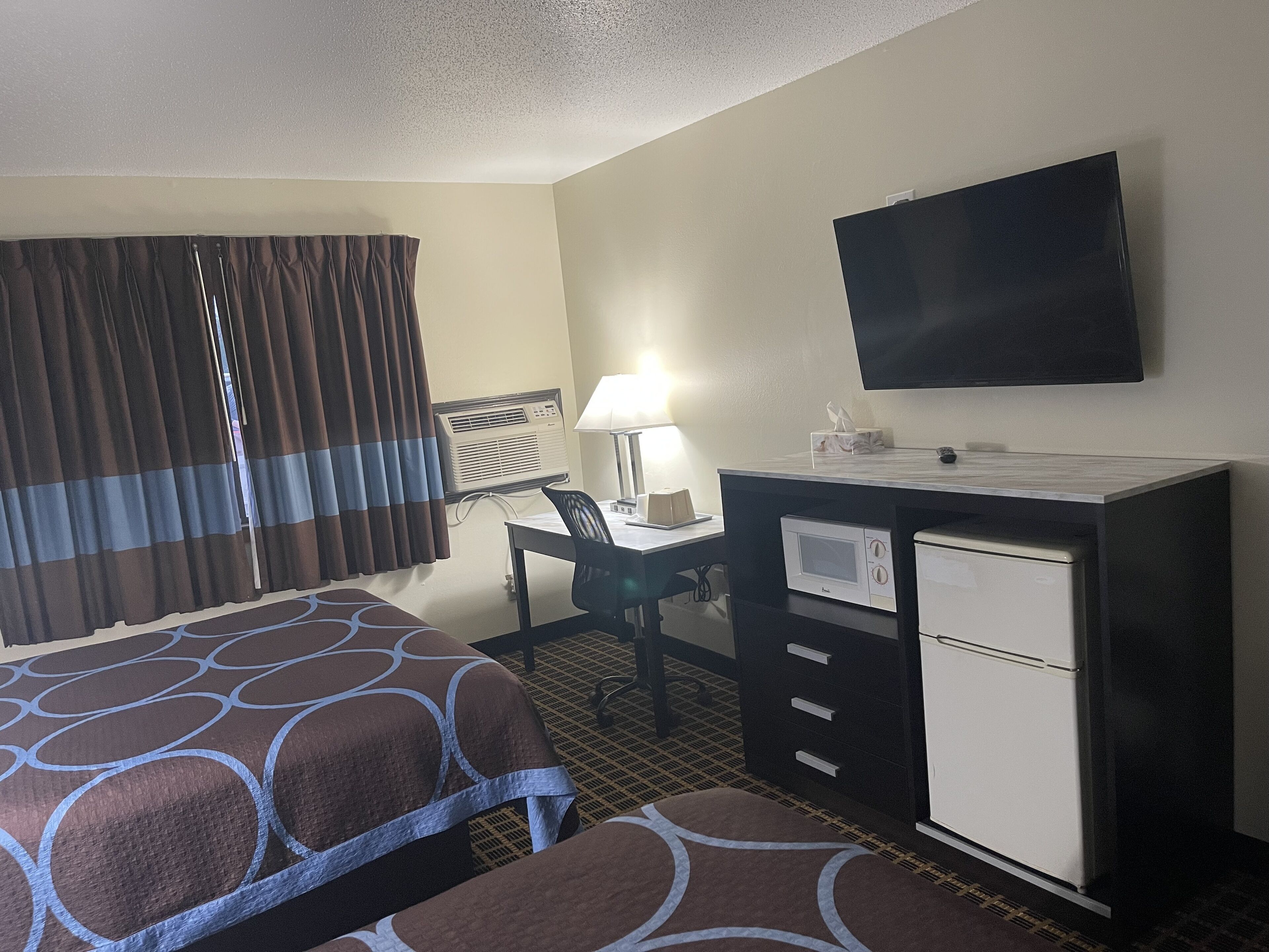 Quarto de hotel com cama, escrivaninha, televisão e minibar.