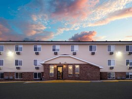 Um hotel com vários andares, entrada de tijolo e várias unidades de ar condicionado.