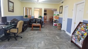 Um saguão de hotel com balcão de recepção, área de estar e uma exposição de revistas.