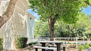 Uma mesa de piquenique em um parque, com um prédio branco ao fundo.
