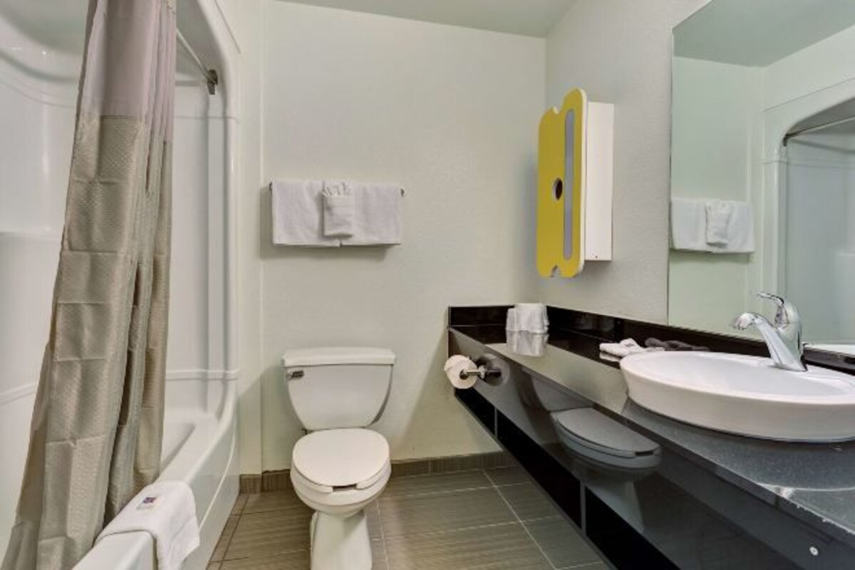 Uma casa de banho moderna com sanita, lavatório e chuveiro.