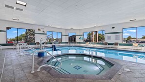 Uma ampla piscina coberta com vista desobstruída para o exterior, rodeada por espreguiçadeiras e um chão revestido de azulejos.