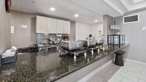 Cozinha moderna com bancadas de granito, eletrodomésticos de aço inoxidável e uma ilha central com banquetas.