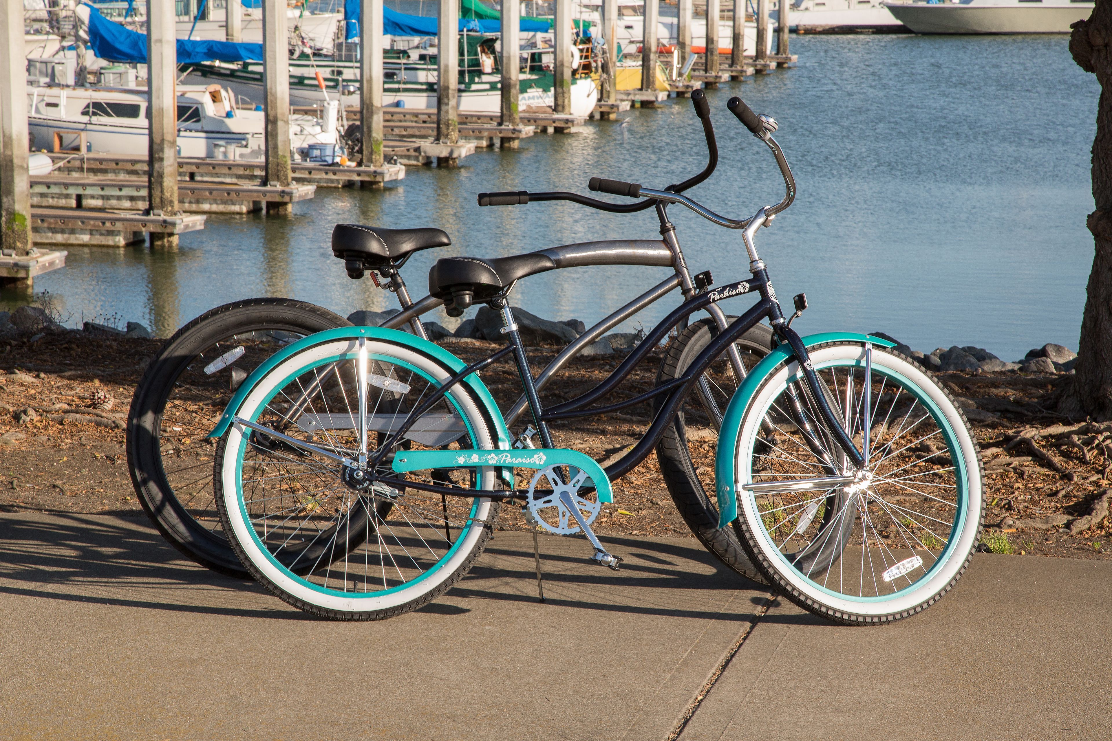 Uma bicicleta estacionada perto de uma orla, com barcos ao fundo.
