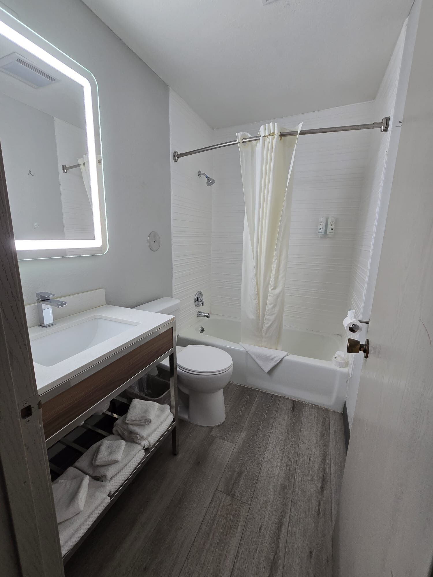 Uma casa de banho moderna com uma sanita, banheira e lavatório brancos.
