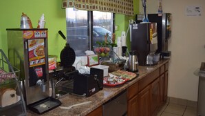 Uma área de café da manhã com máquina de café, geladeira e janela com vista para o exterior.