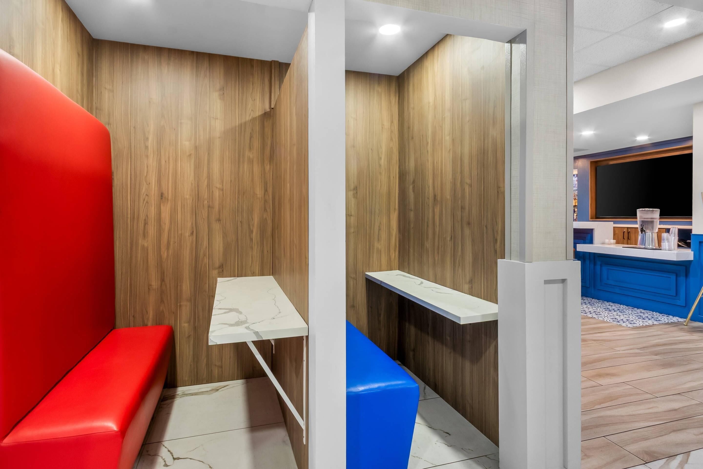 Um interior moderno com um banco vermelho, uma mesa branca e um balcão azul.
