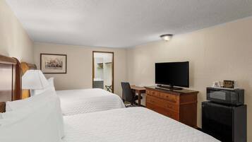 Quarto de hotel com duas camas, uma escrivaninha, televisão, frigorífico e espelho.