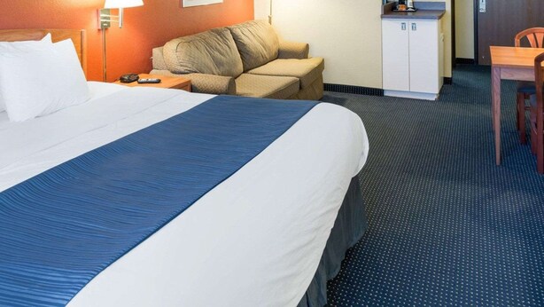 Quarto de hotel com uma cama grande, um sofá, uma escrivaninha e um espelho.