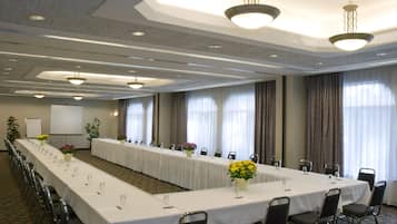 Uma sala de conferências com uma mesa comprida, cadeiras e um projetor.