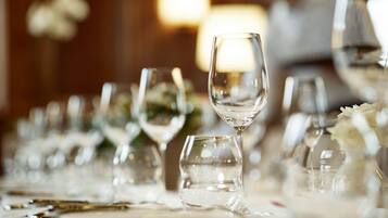 Mesa posta com várias taças de vinho e talheres, indicando uma refeição formal.