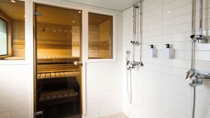 Um banheiro moderno com sauna de madeira, paredes revestidas de azulejos brancos e área de chuveiro.