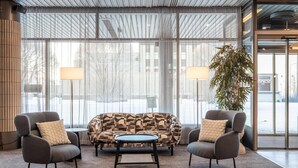 Um hall moderno com um sofá e poltronas, uma mesa de centro e uma planta grande.