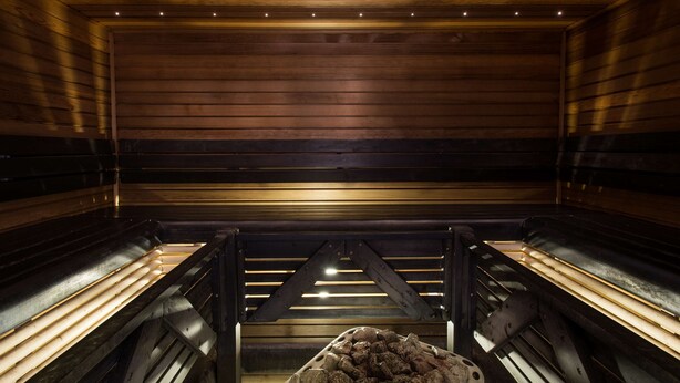 Uma sauna com bancos de madeira e um monte de pedras no centro.