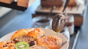 Um prato com diversos doces e pães, com uma colher derramando calda.