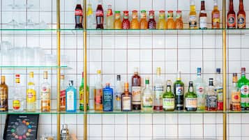 Uma área de bar com prateleiras cheias de garrafas de bebidas e copos.