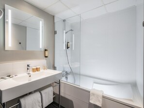 Casa de banho moderna com um espelho grande, uma sanita branca, uma banheira e um box de chuveiro em vidro.