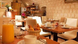 Ambiente de café da manhã com mesas, cadeiras e uma área de cozinha ao fundo.