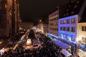 Um edifício histórico com arquitetura gótica, uma catedral e um hotel com letreiros iluminados.