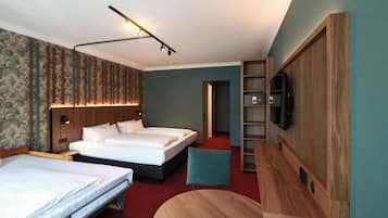Quarto de hotel com duas camas, televisão, escrivaninha de madeira e tapete vermelho.